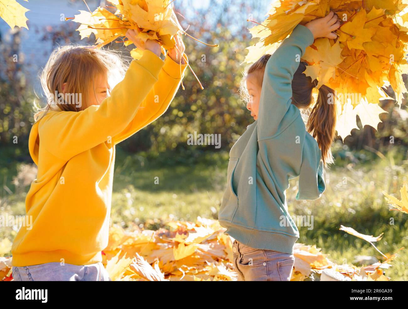 Girls kids playing jumping on trampoline with autumn leaves. Bright ...