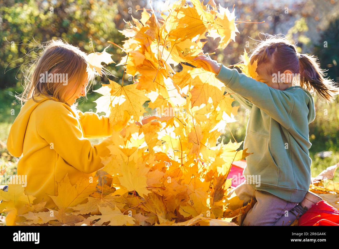 Girls kids playing jumping on trampoline with autumn leaves. Bright ...