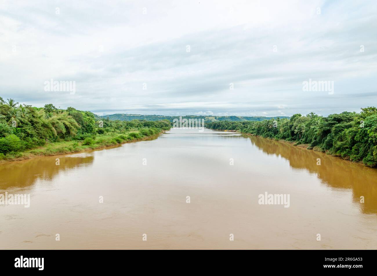 River with lush green river bank and muddy rain water at Polali ...