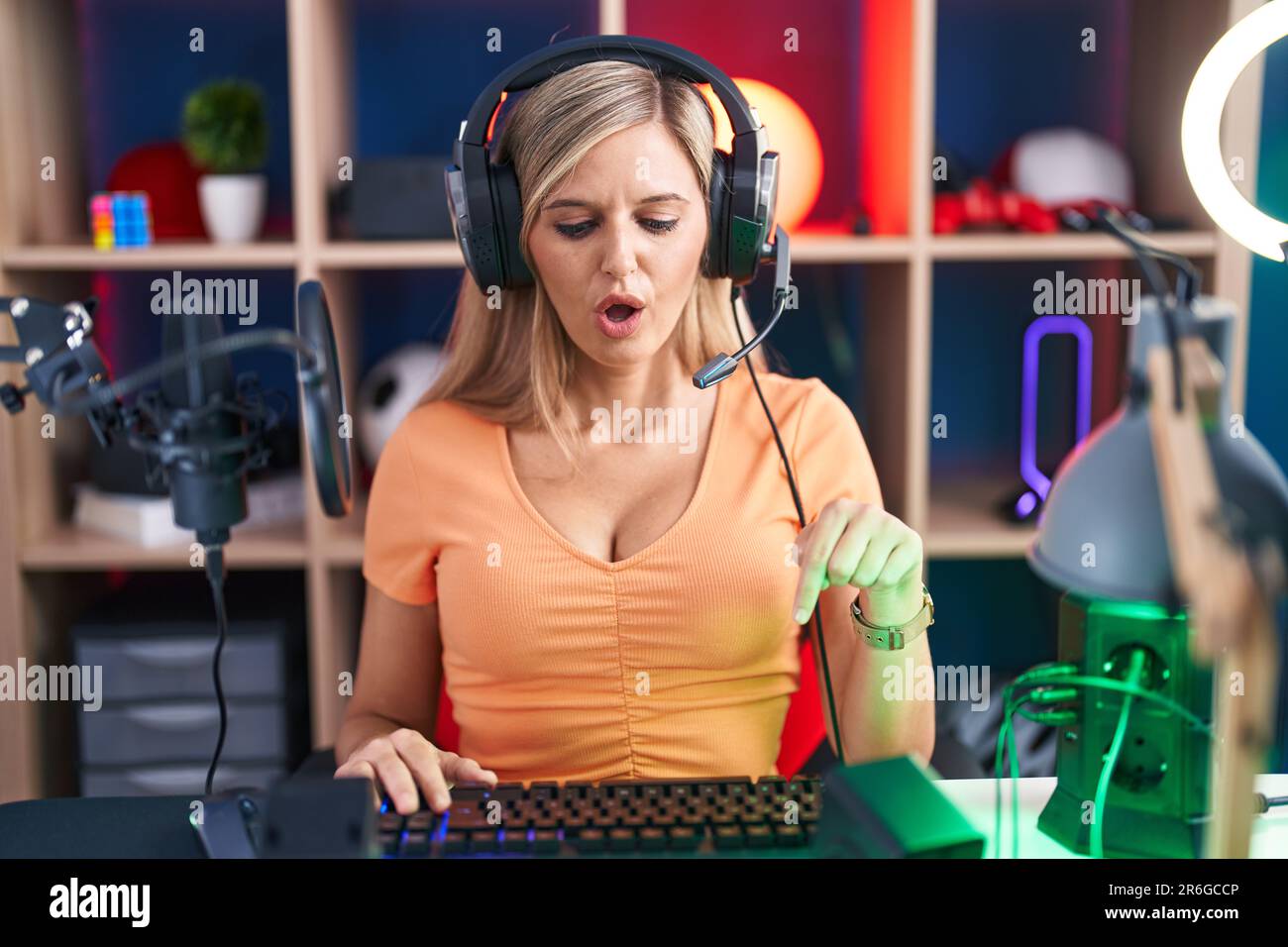 Young woman playing video games pointing down with fingers showing ...