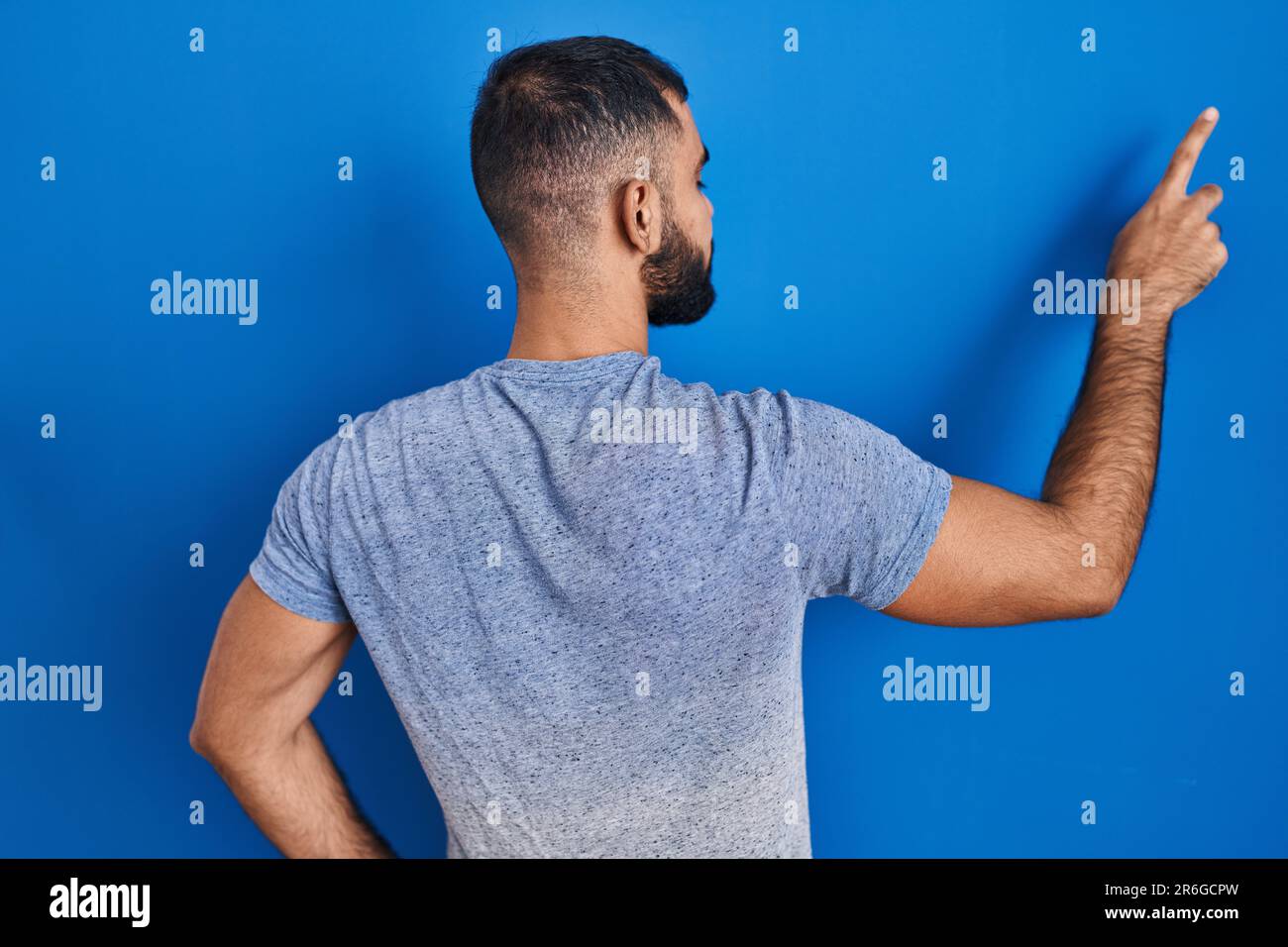 Middle east man with beard standing over blue background posing ...