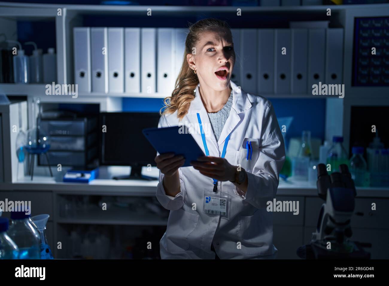 Beautiful blonde woman working at scientist laboratory late at night ...