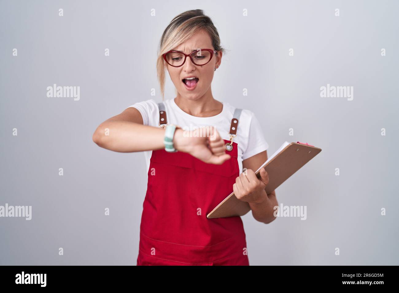 Young blonde woman wearing waiter uniform holding clipboard looking at ...