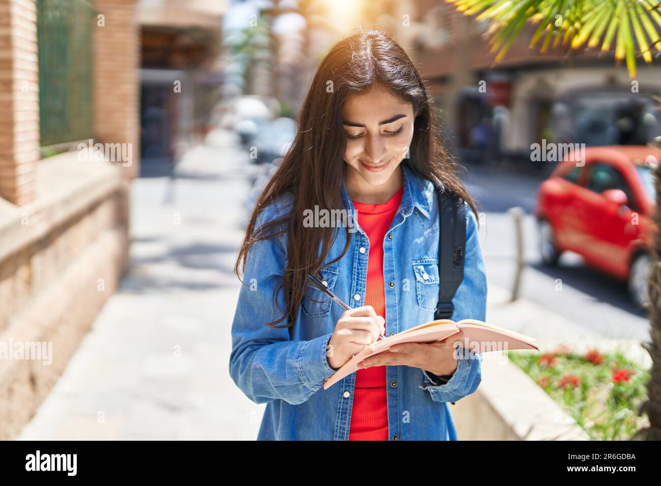 Young hispanic girl student writing on notebook at street Stock Photo ...