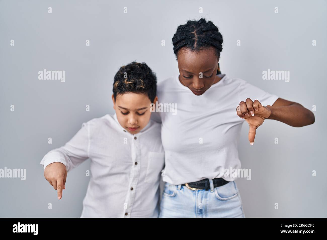 Young mother and son standing together over white background pointing ...