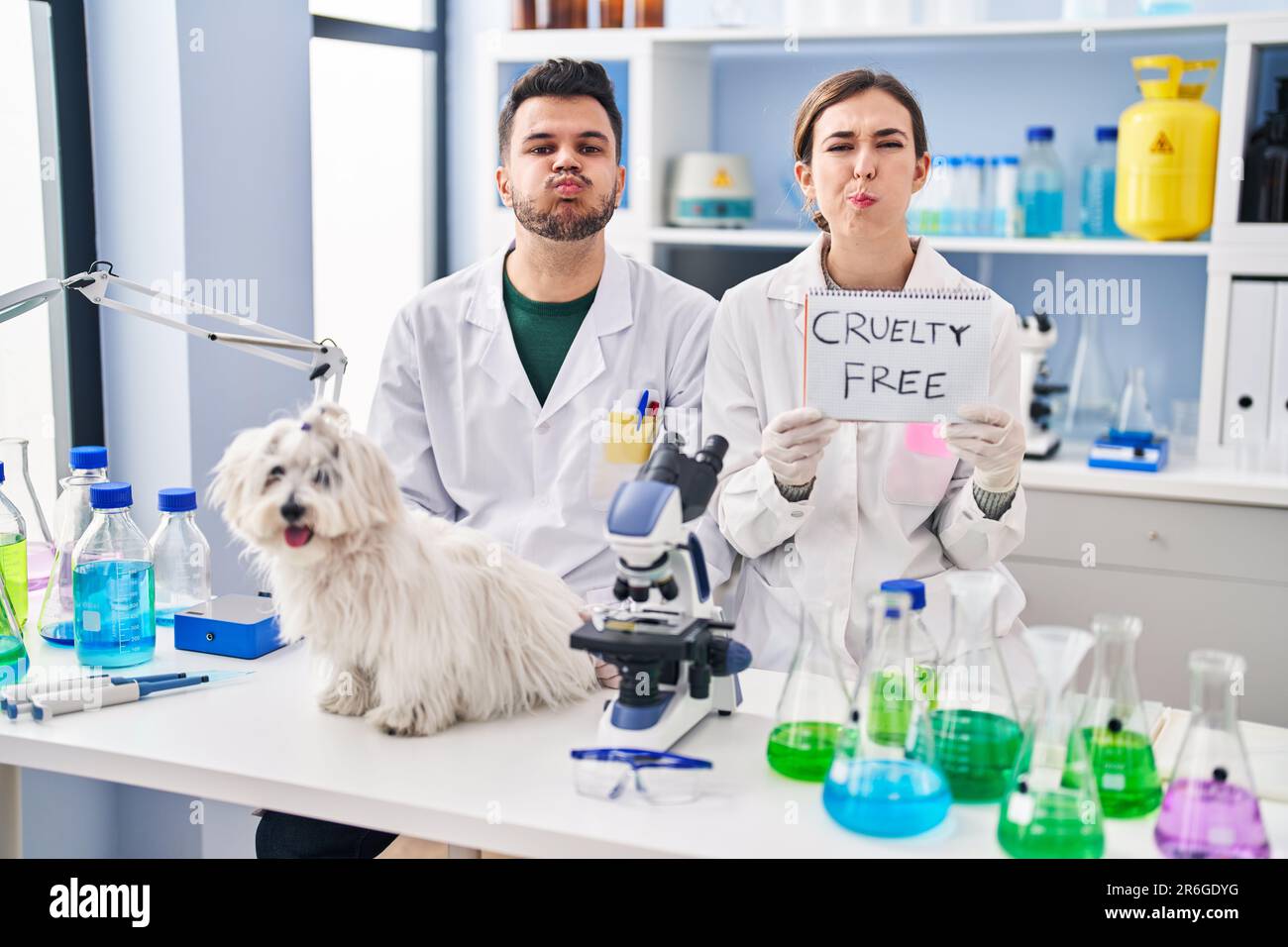 Young hispanic people working at scientist laboratory with dog puffing ...