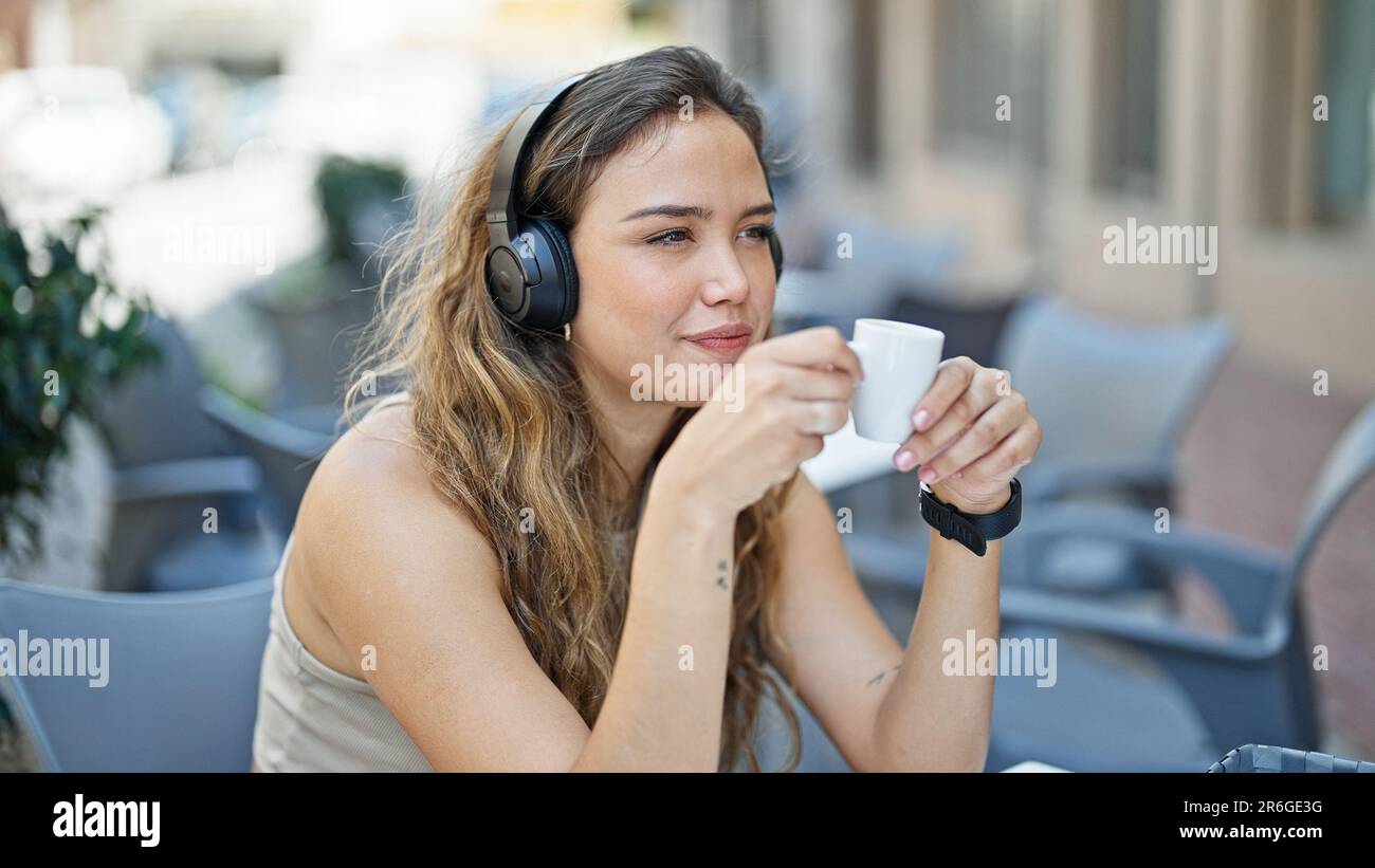 Young beautiful hispanic woman listening to music drinking coffee at ...