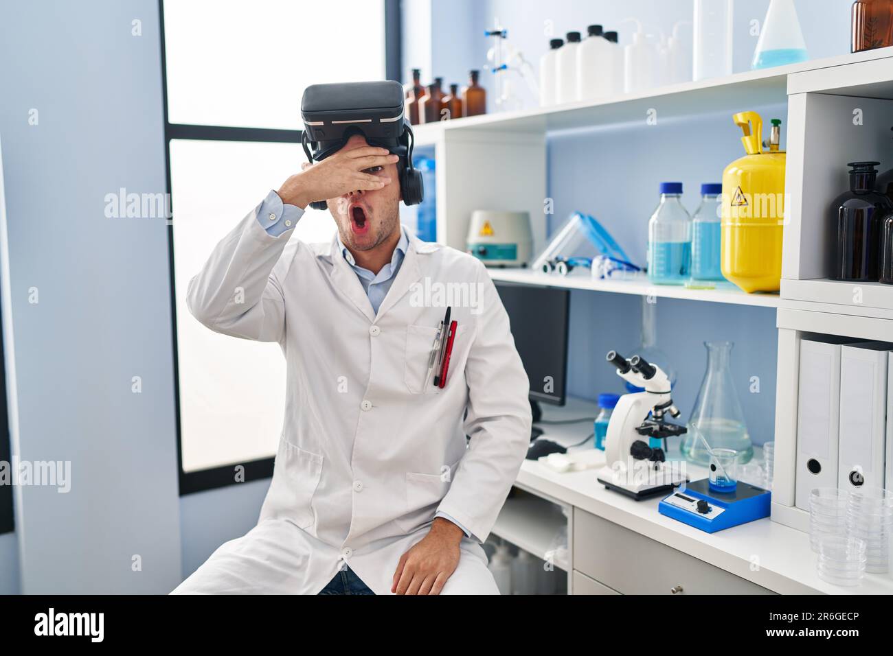 Young hispanic man working at scientist laboratory wearing vr glasses ...