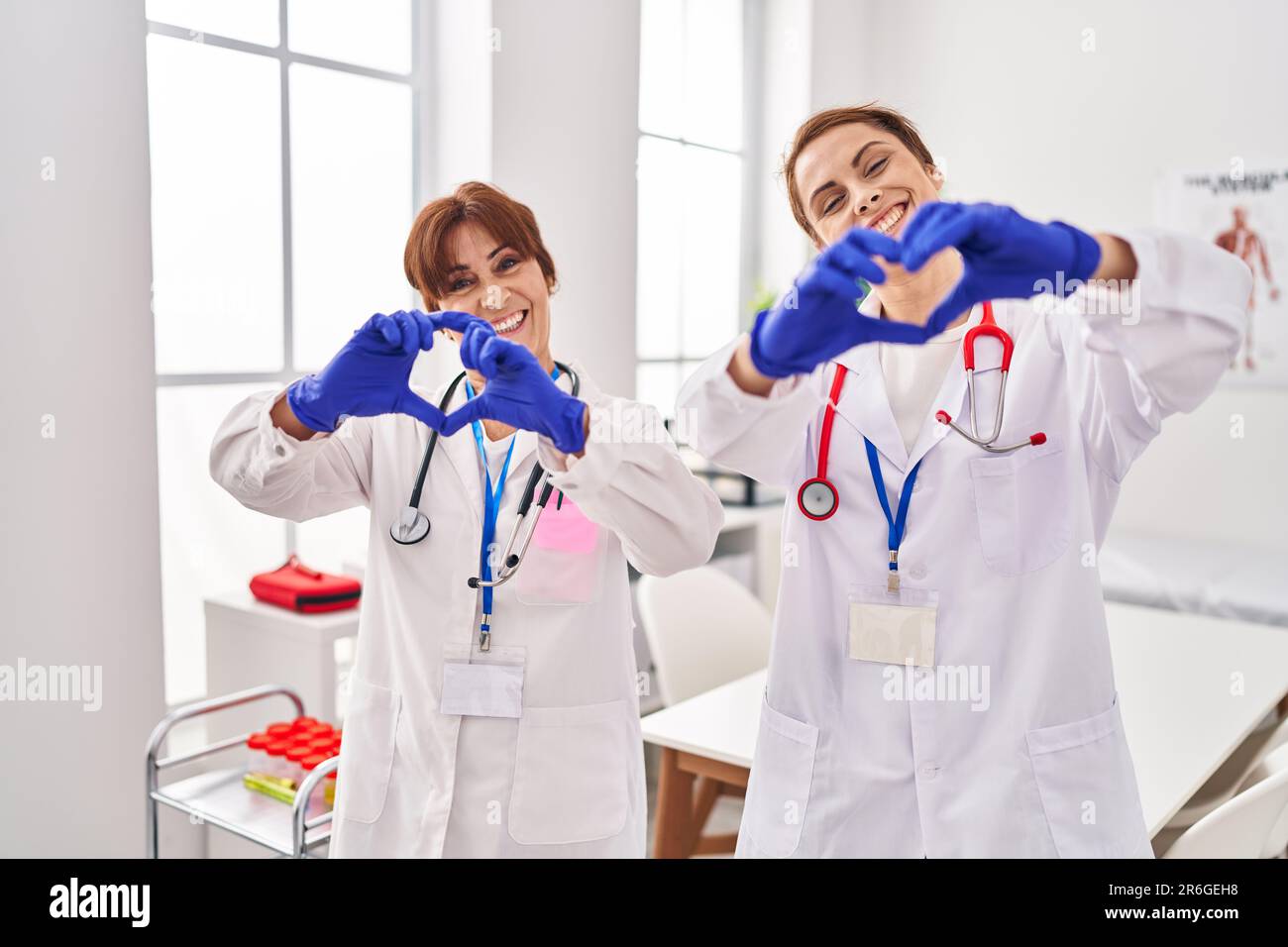 Two women wearing doctor uniform and stethoscope smiling in love ...
