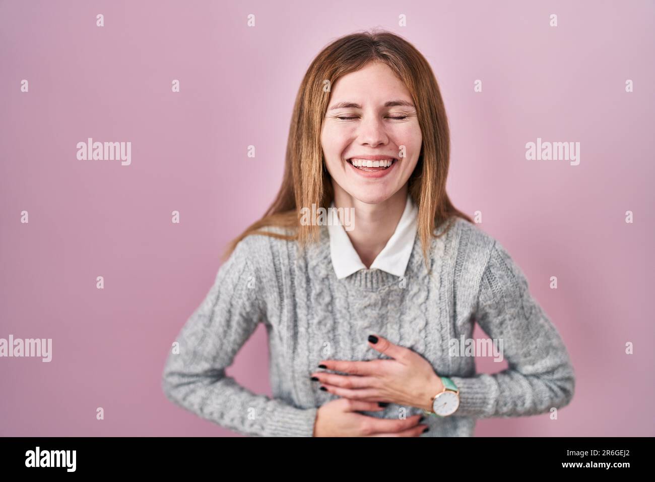 Beautiful woman standing over pink background smiling and laughing hard ...