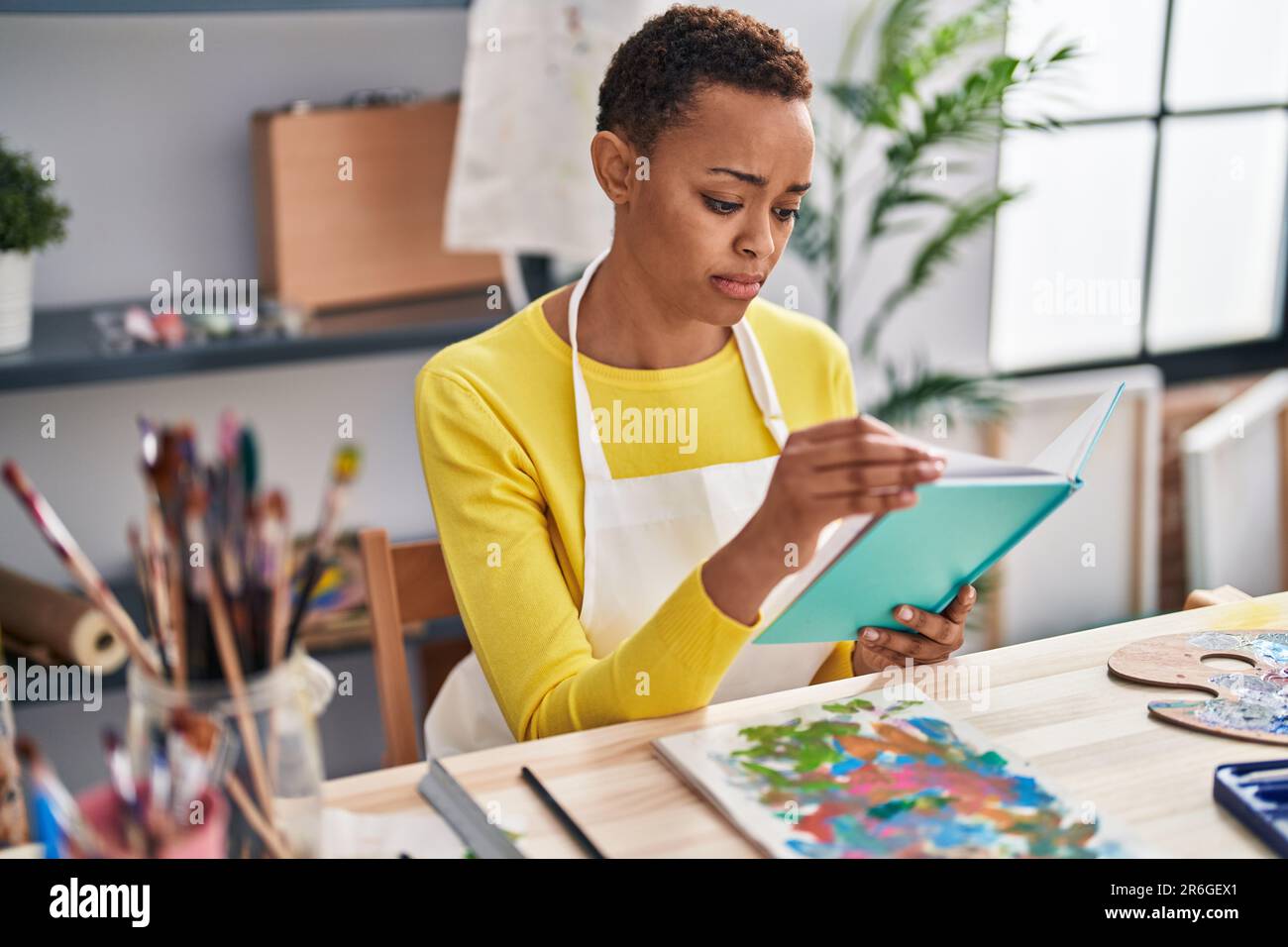 African american woman artist reading book with serious expression at ...