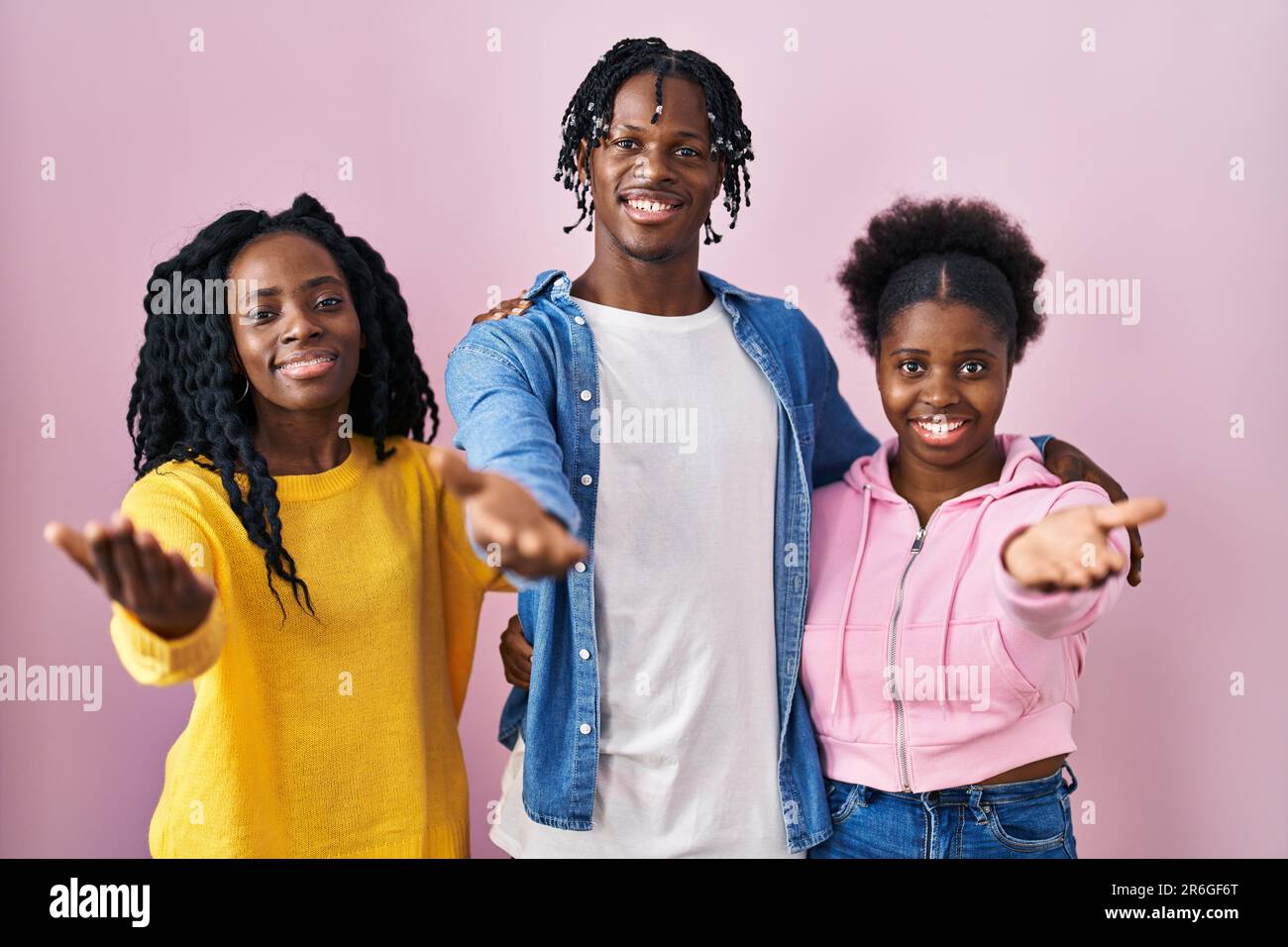 Group of three young black people standing together over pink ...