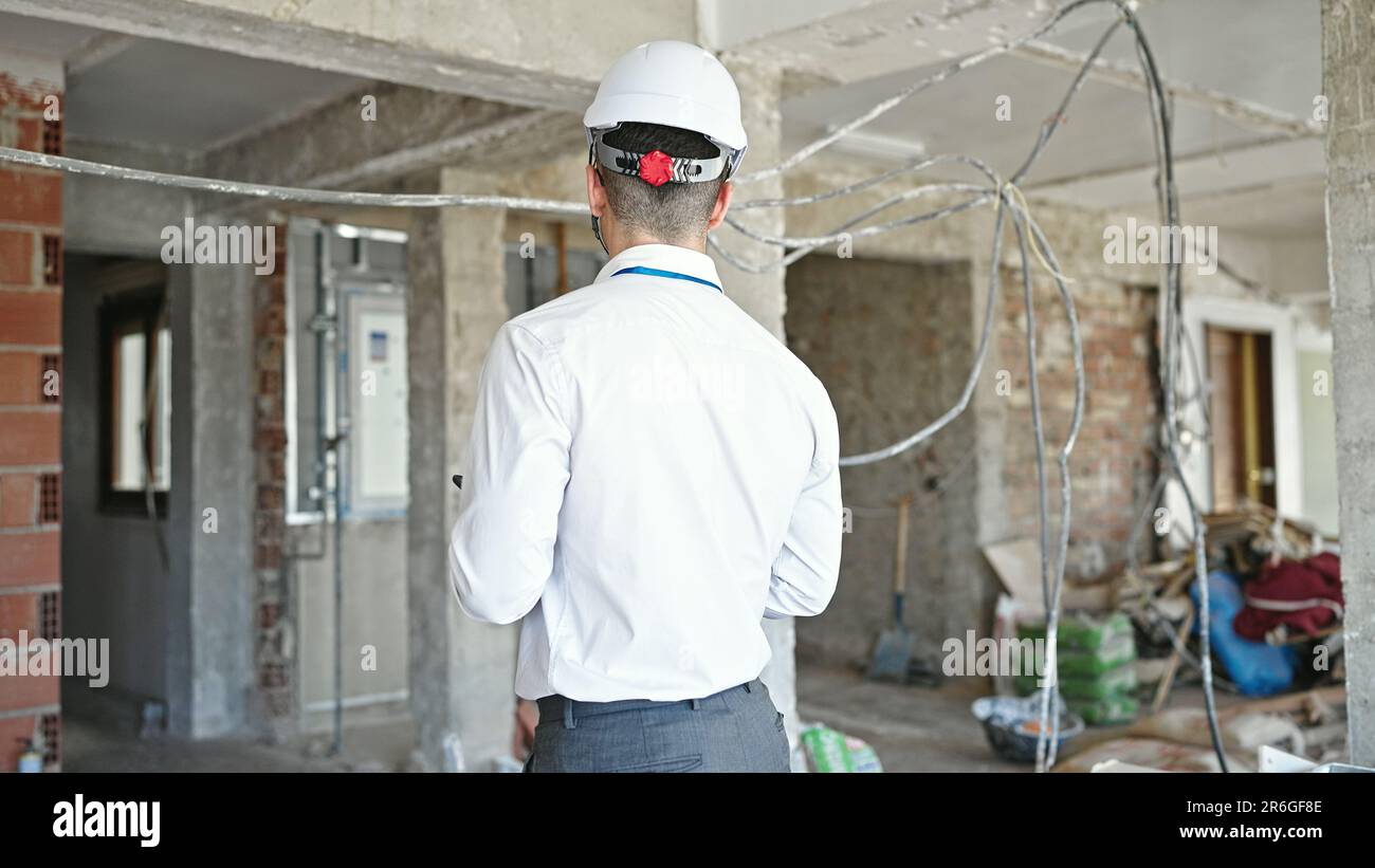 Young hispanic man architect standing backwards at construction site ...