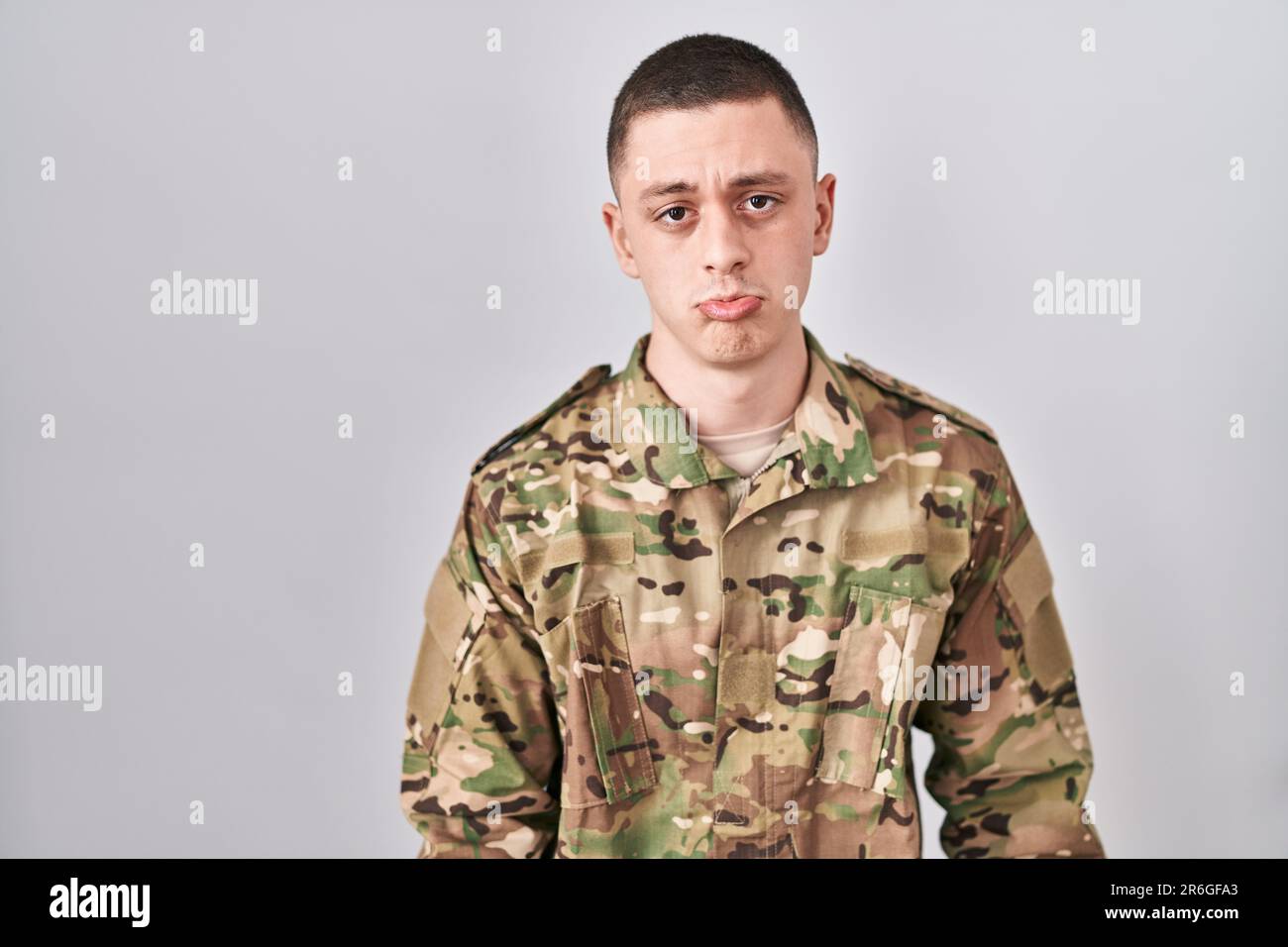 Young man wearing camouflage army uniform depressed and worry for ...