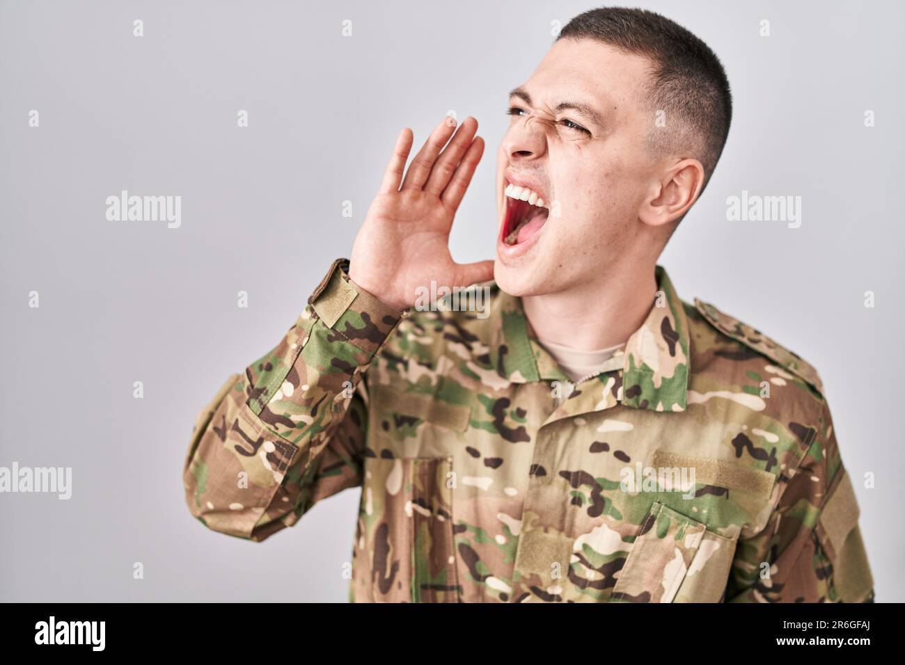 Young man wearing camouflage army uniform shouting and screaming loud ...