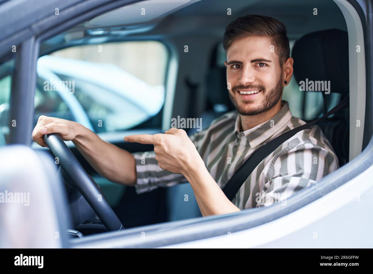 Hispanic man with beard driving car smiling happy pointing with hand ...