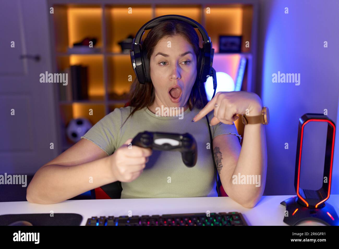 Beautiful brunette woman playing video games wearing headphones ...