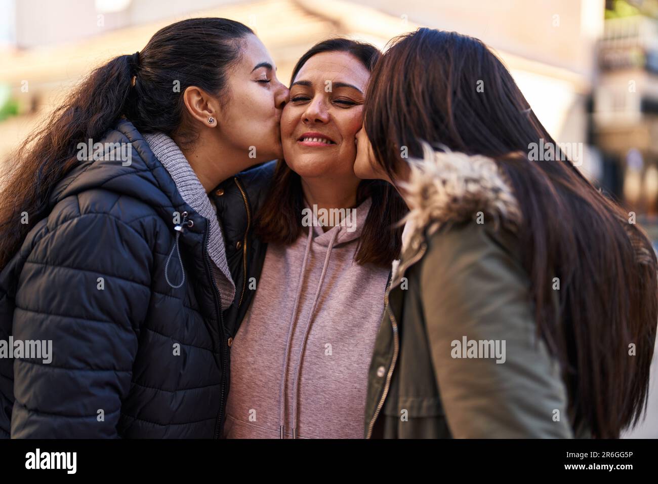 Three woman mother and daughters standing together and kissing at ...