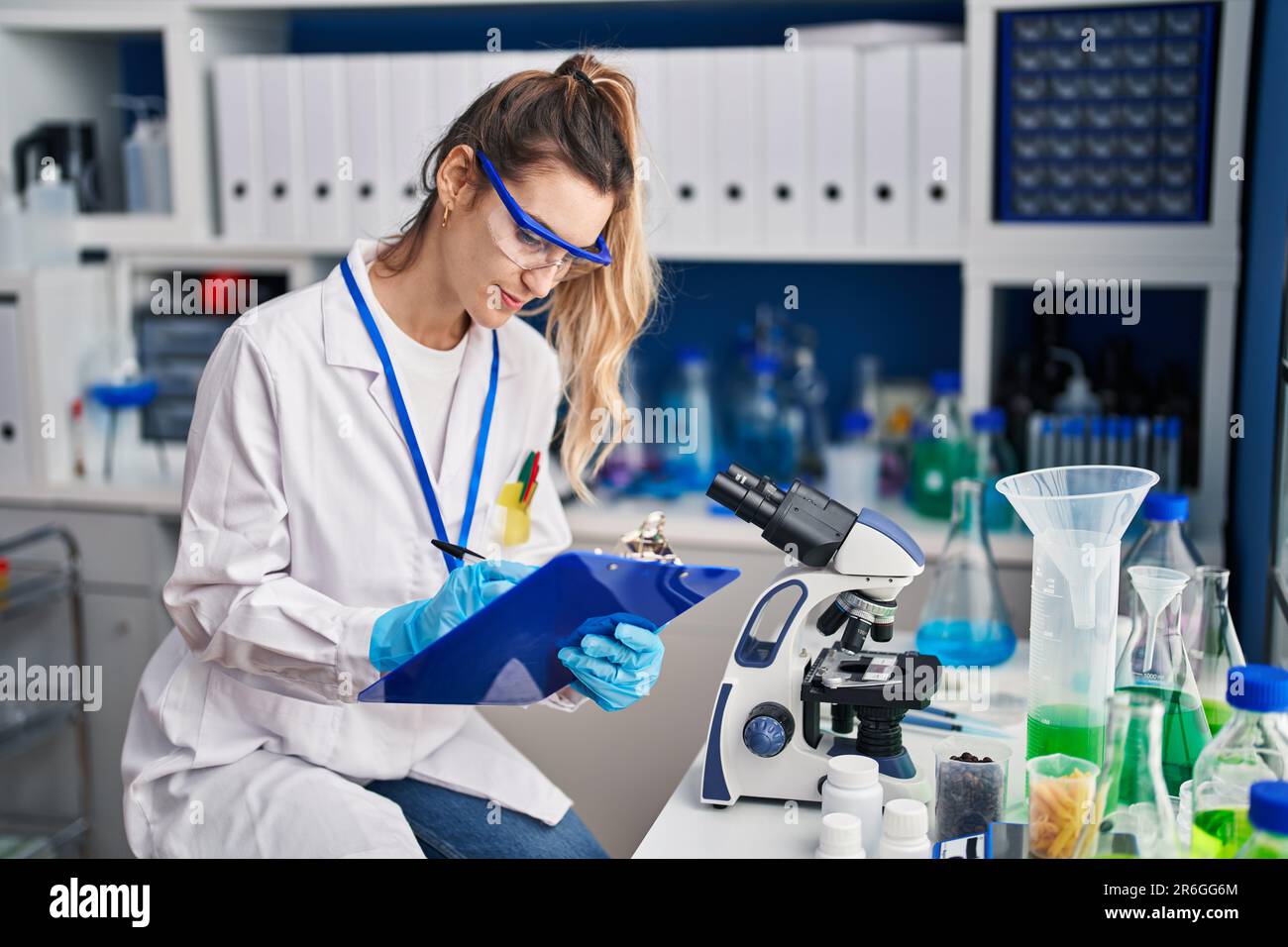 Young woman scientist smiling confident writing medical report at ...