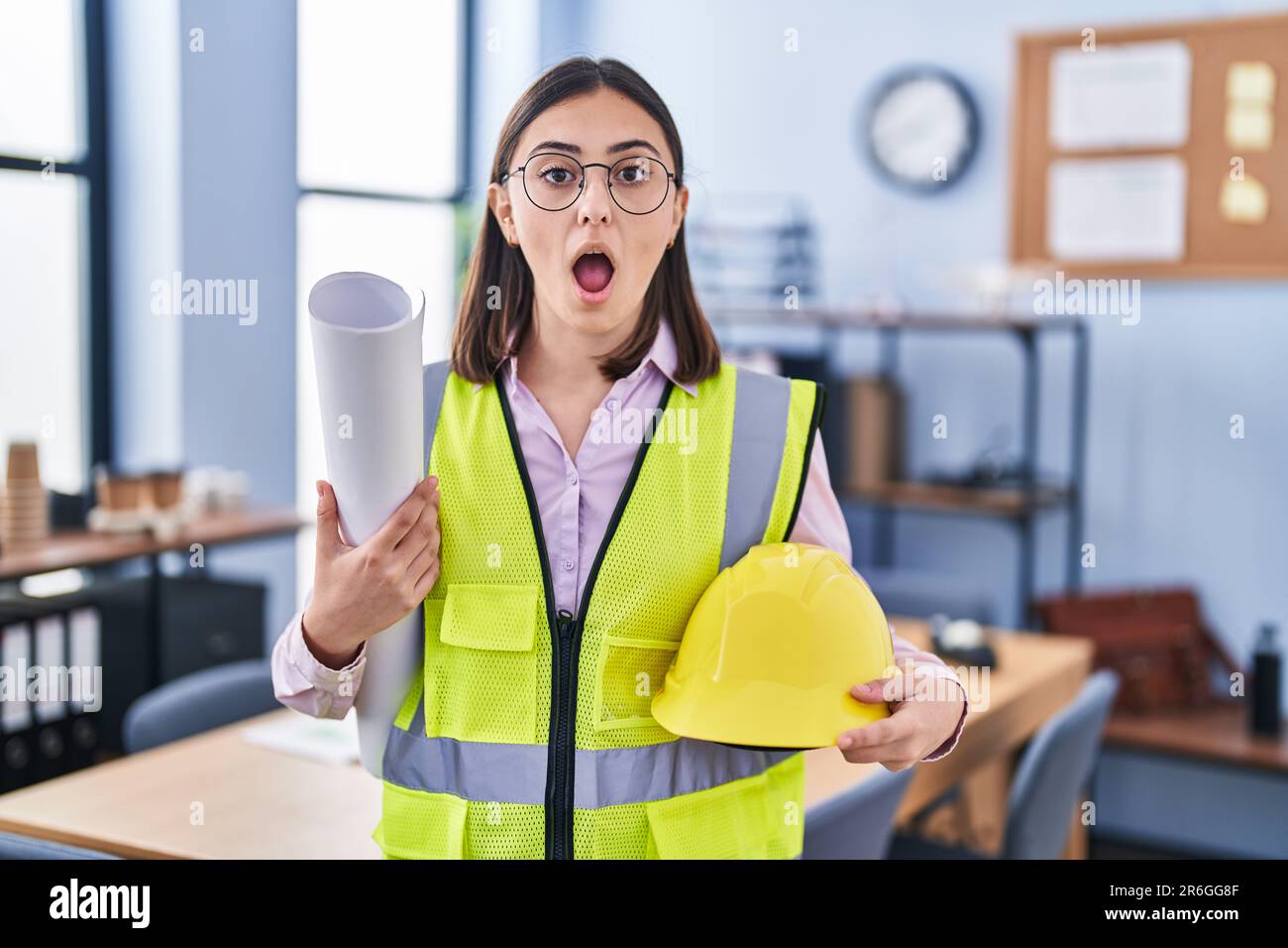 Hispanic girl architect holding build project blueprints afraid and ...
