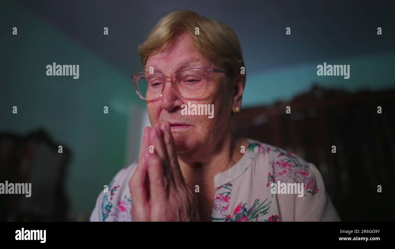 Religious Elderly woman Praying to God at home. Close-up face of a ...