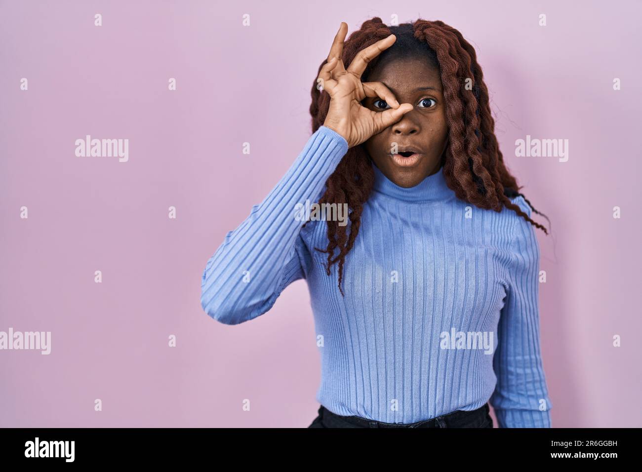 African woman standing over pink background doing ok gesture shocked ...