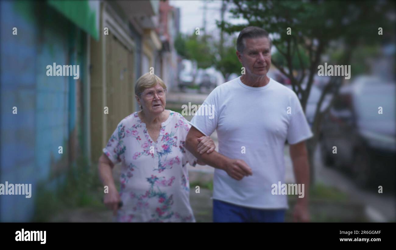 Supportive Walk of Adult Son Assisting Elderly Mother, Embracing ...