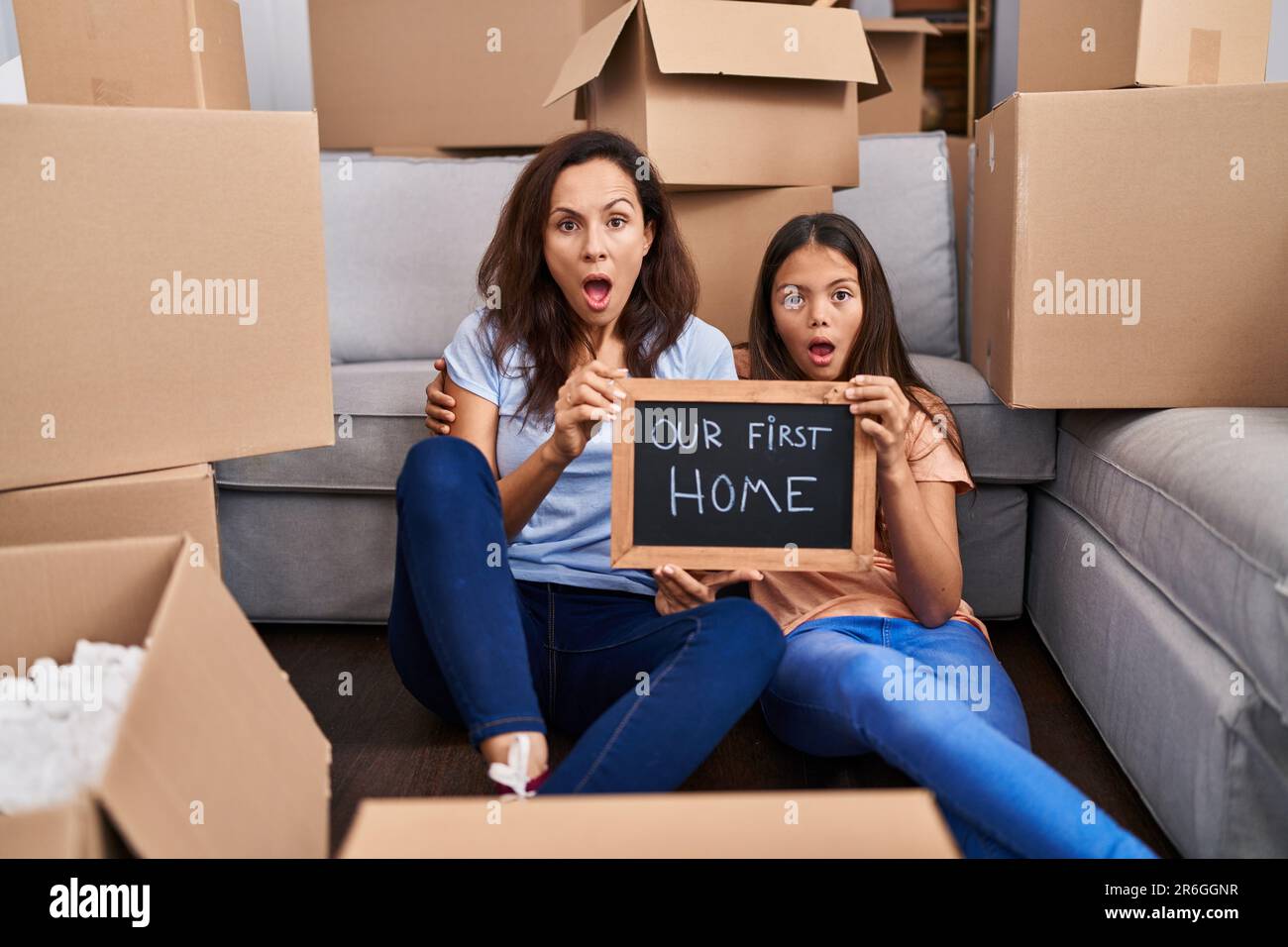 Young mother and daughter sitting on the floor at new home in shock ...