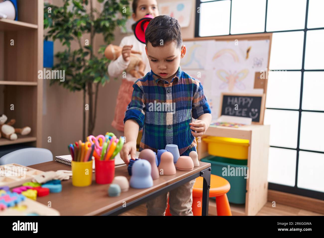 Adorable boy and girl standing with relaxed expression playing at ...