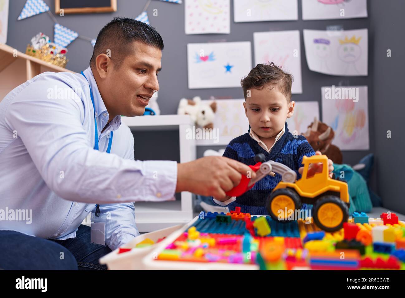 Hispanic man and boy playing with construction blocks and tractor toy ...