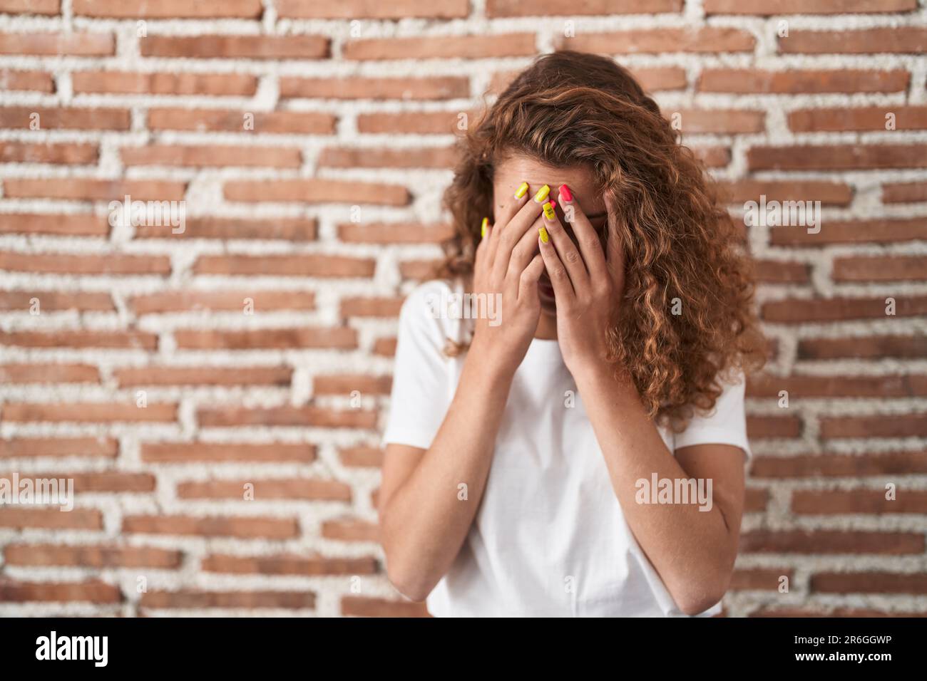 Young caucasian woman standing over bricks wall background with sad ...