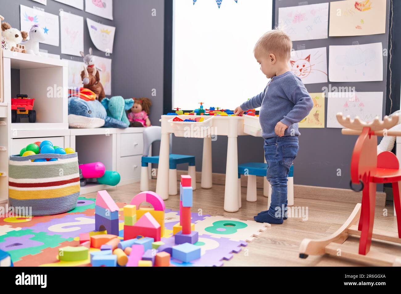 Adorable caucasian boy playing with construction blocks standing at ...