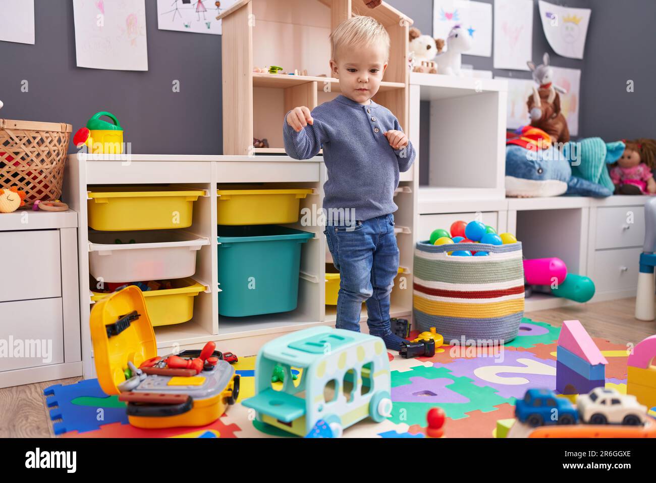Adorable caucasian boy standing with relaxed expression playing at ...