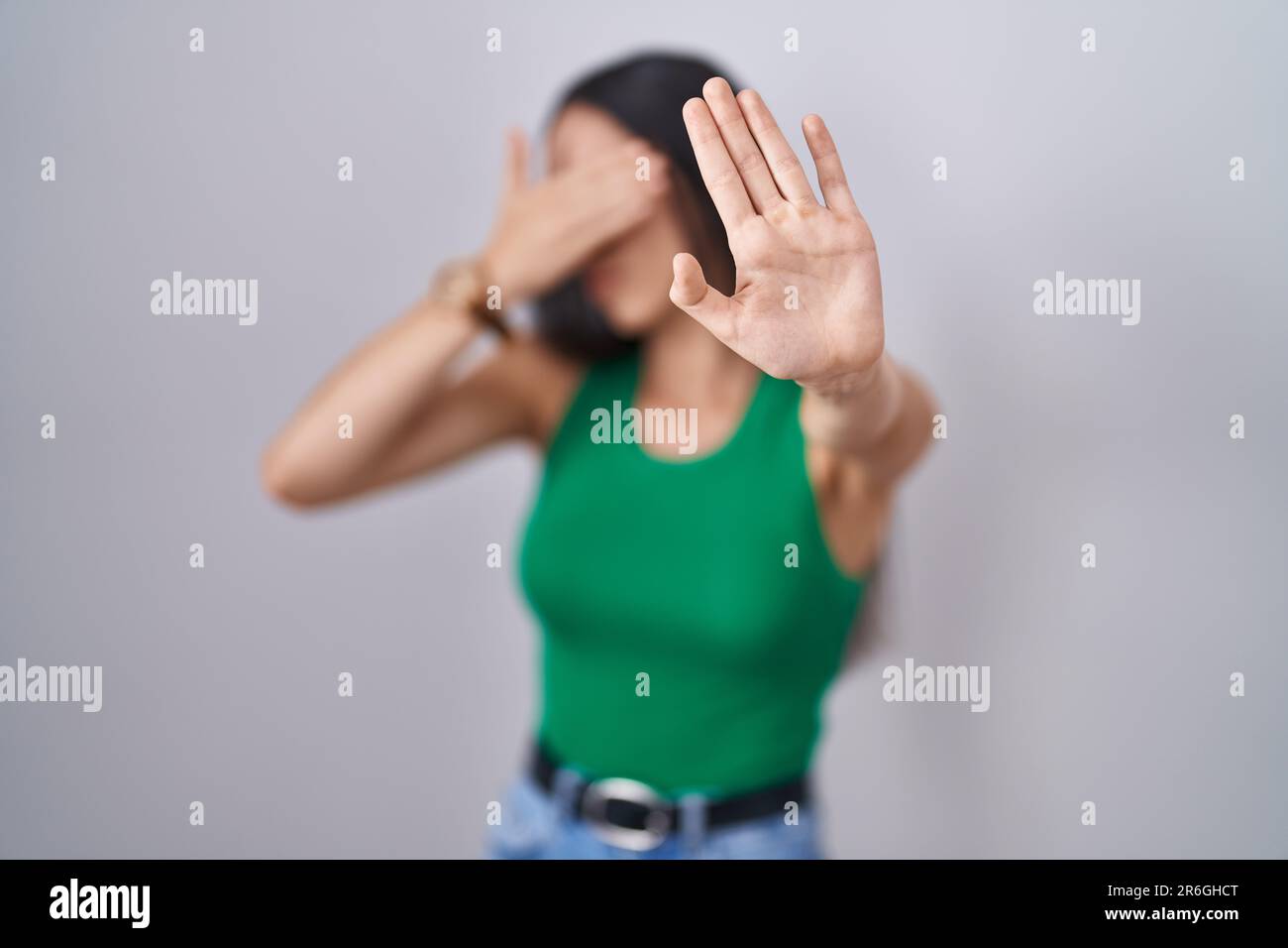 Young woman standing over isolated background covering eyes with hands ...