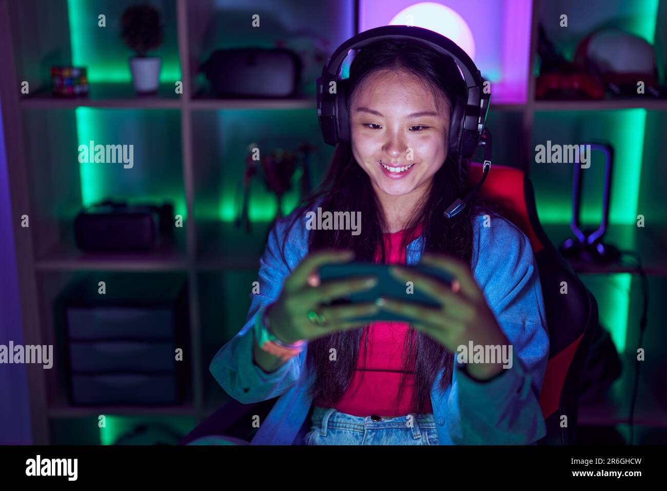 Young chinese woman streamer playing video game using smartphone at ...