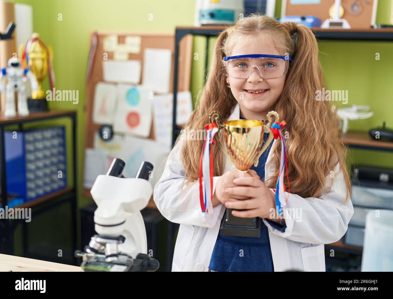 Adorable blonde girl student smiling confident holding gold trophy at ...