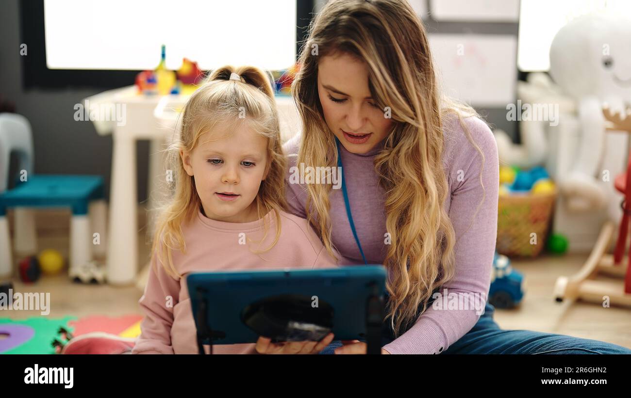 Woman and girl having lesson using touchpad at kindergarten Stock Photo ...