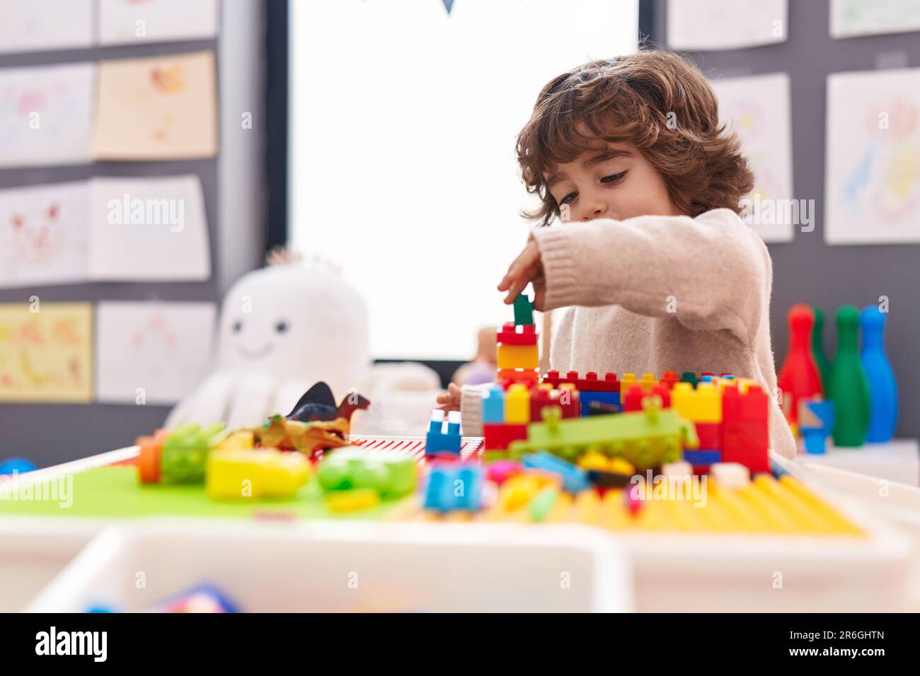 Adorable hispanic boy playing with construction blocks standing at ...