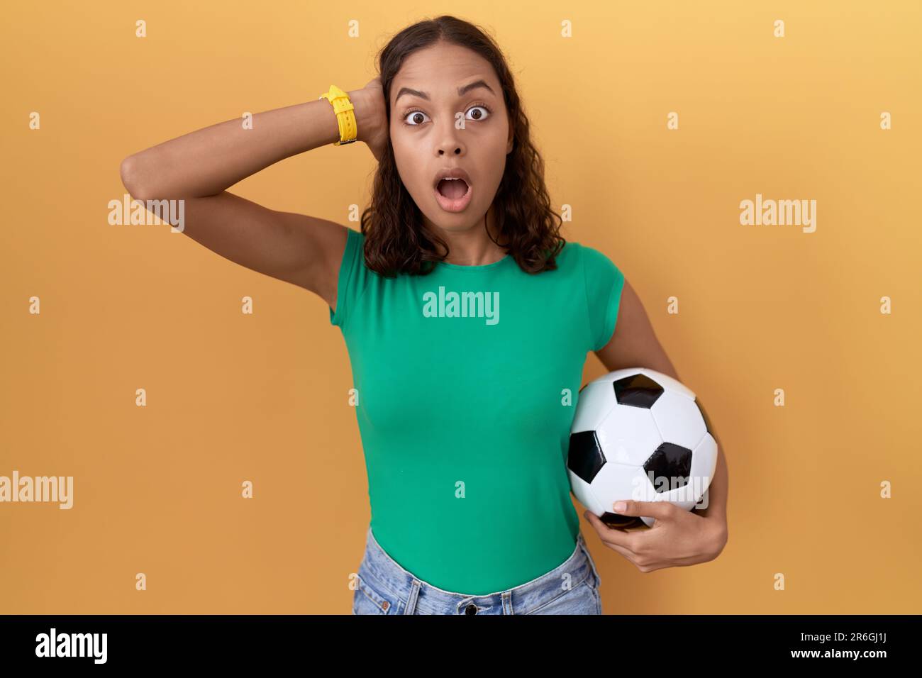 Young hispanic woman holding ball crazy and scared with hands on head ...