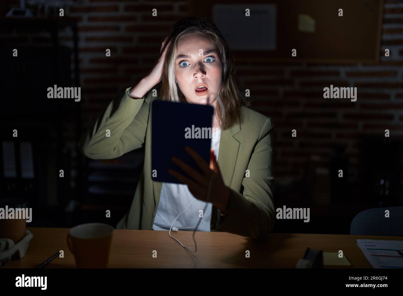 Blonde caucasian woman working at the office at night crazy and scared ...