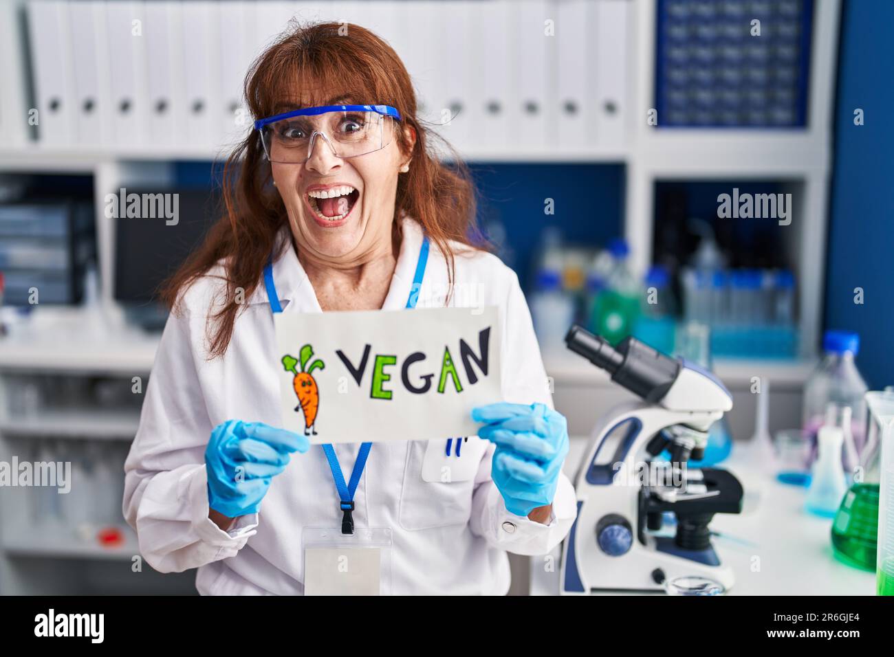 Middle age hispanic woman working at vegan laboratory celebrating crazy ...
