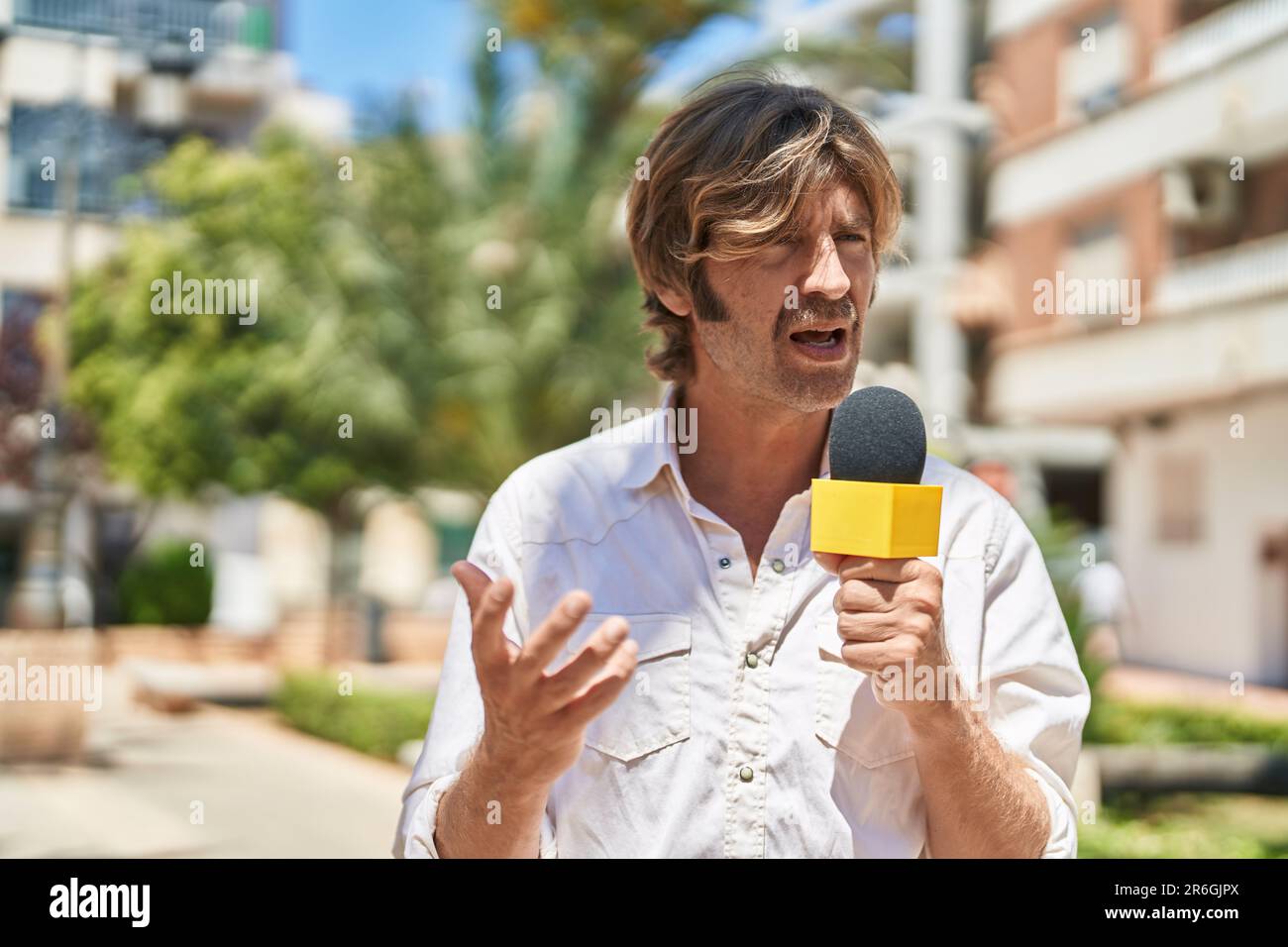 Young man reporter working using microphone at park Stock Photo - Alamy