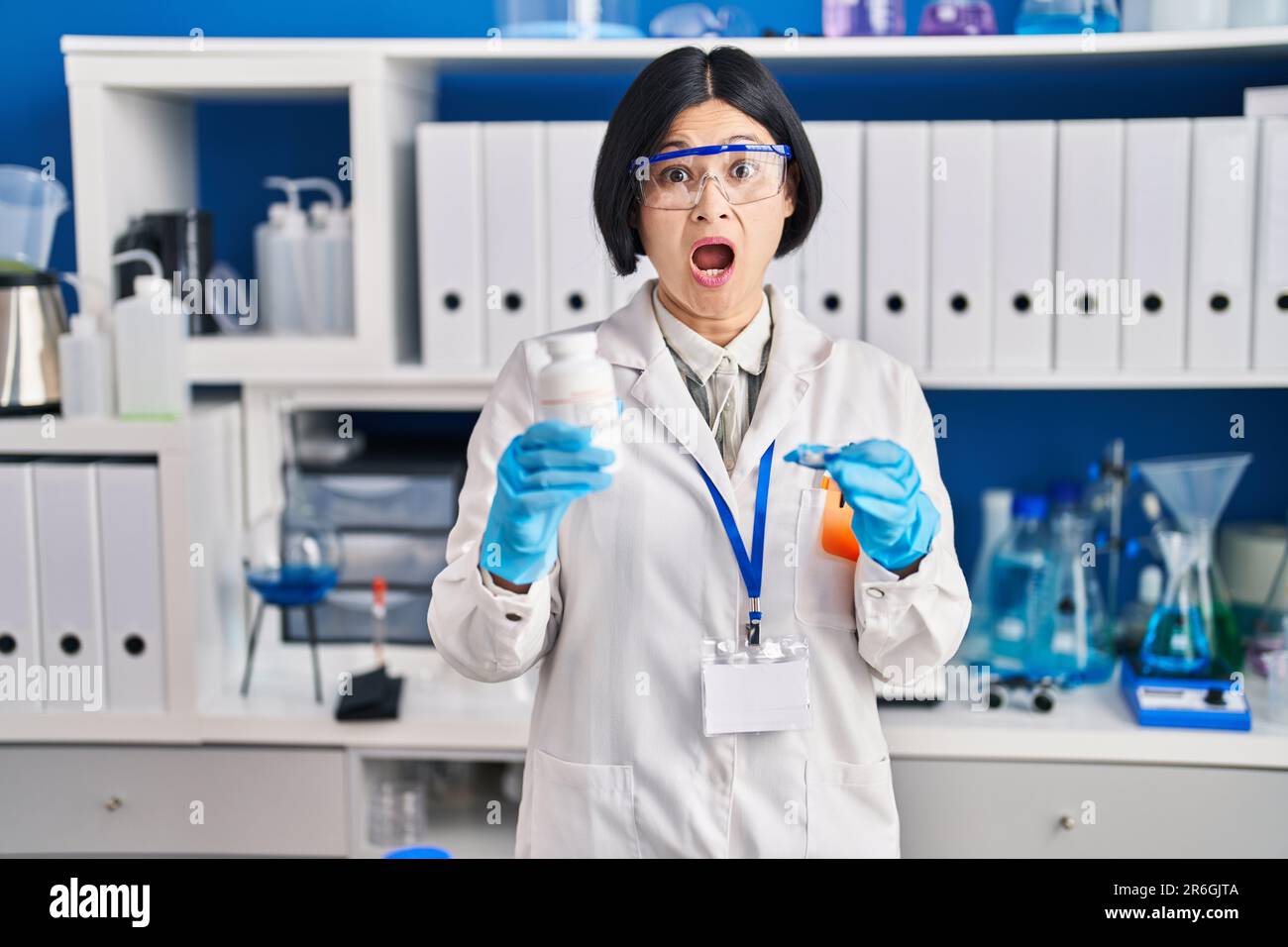 Young asian woman working at scientist laboratory afraid and shocked ...