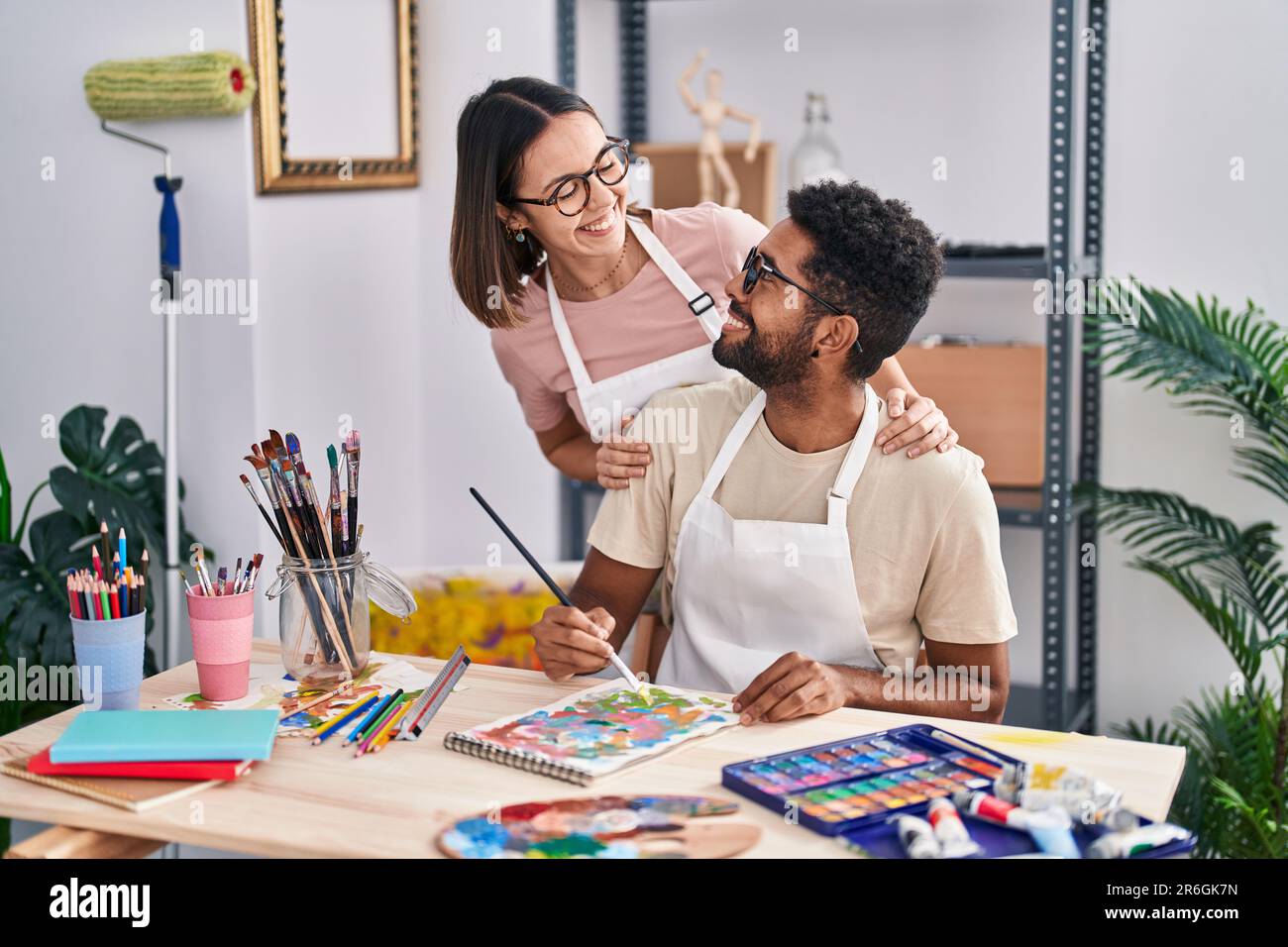 Man and woman artists smiling confident drawing on notebook at art ...