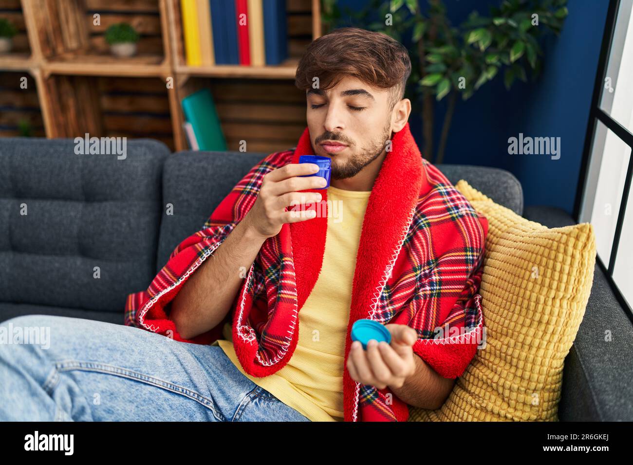 Young arab man smelling mint medication sitting on sofa at home Stock ...