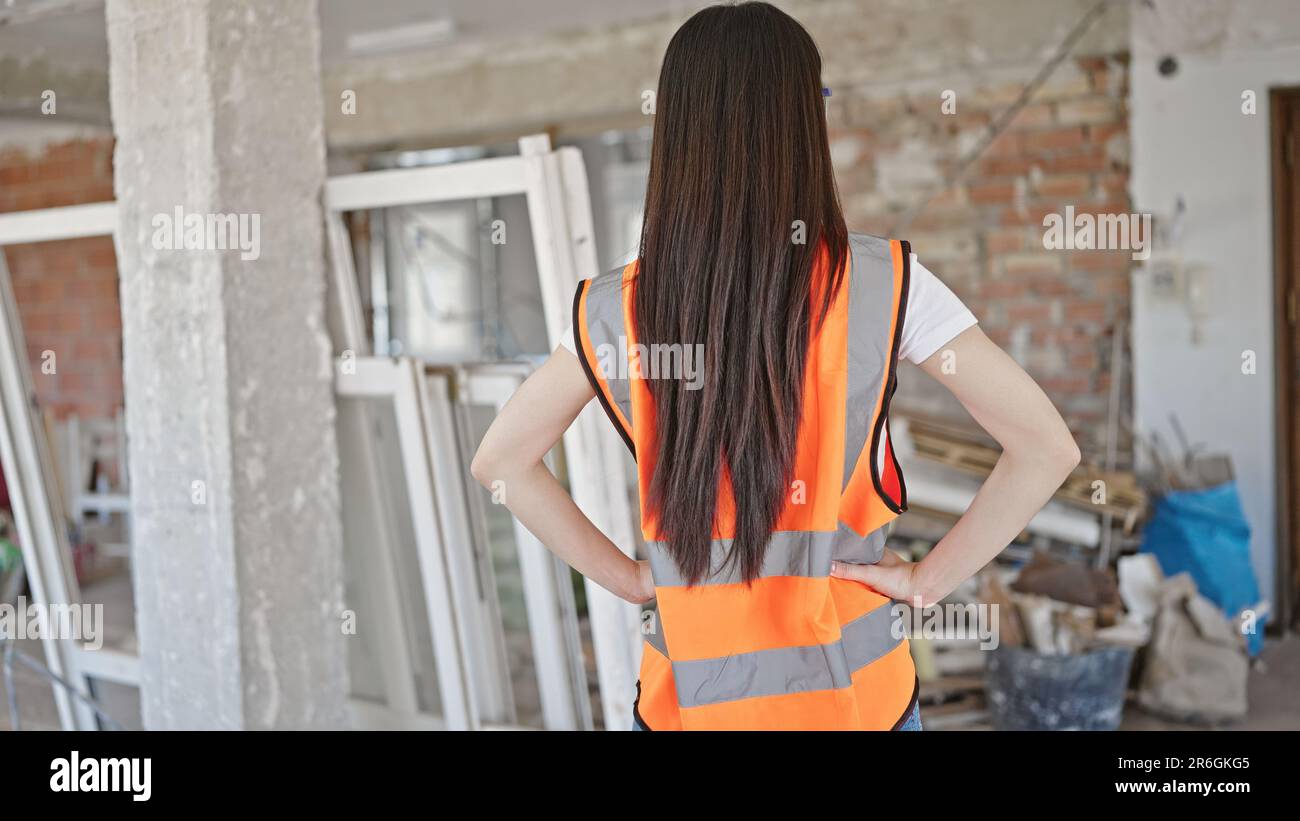 Young chinese woman builder standing backwards at construction site ...