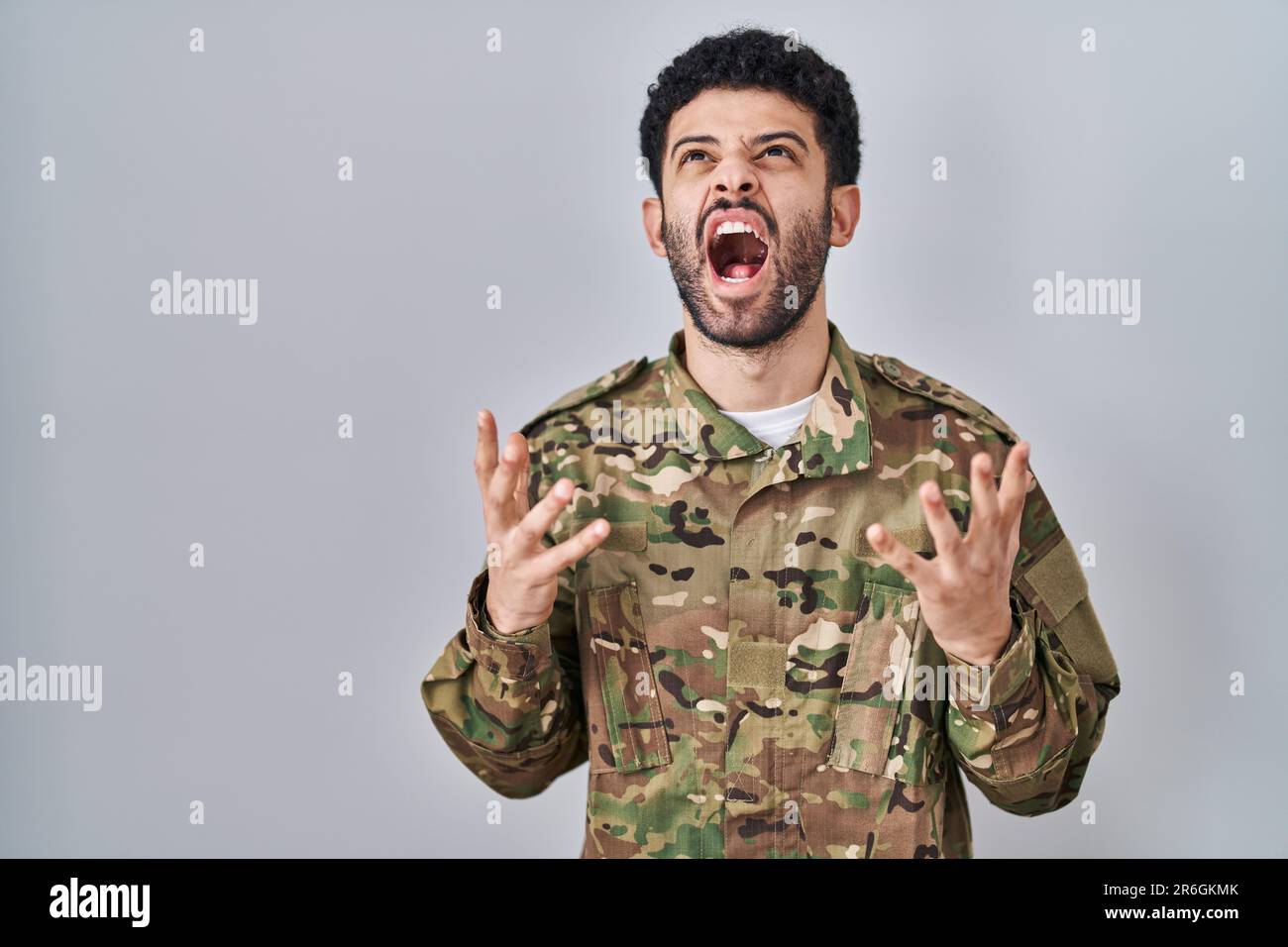 Arab man wearing camouflage army uniform crazy and mad shouting and ...