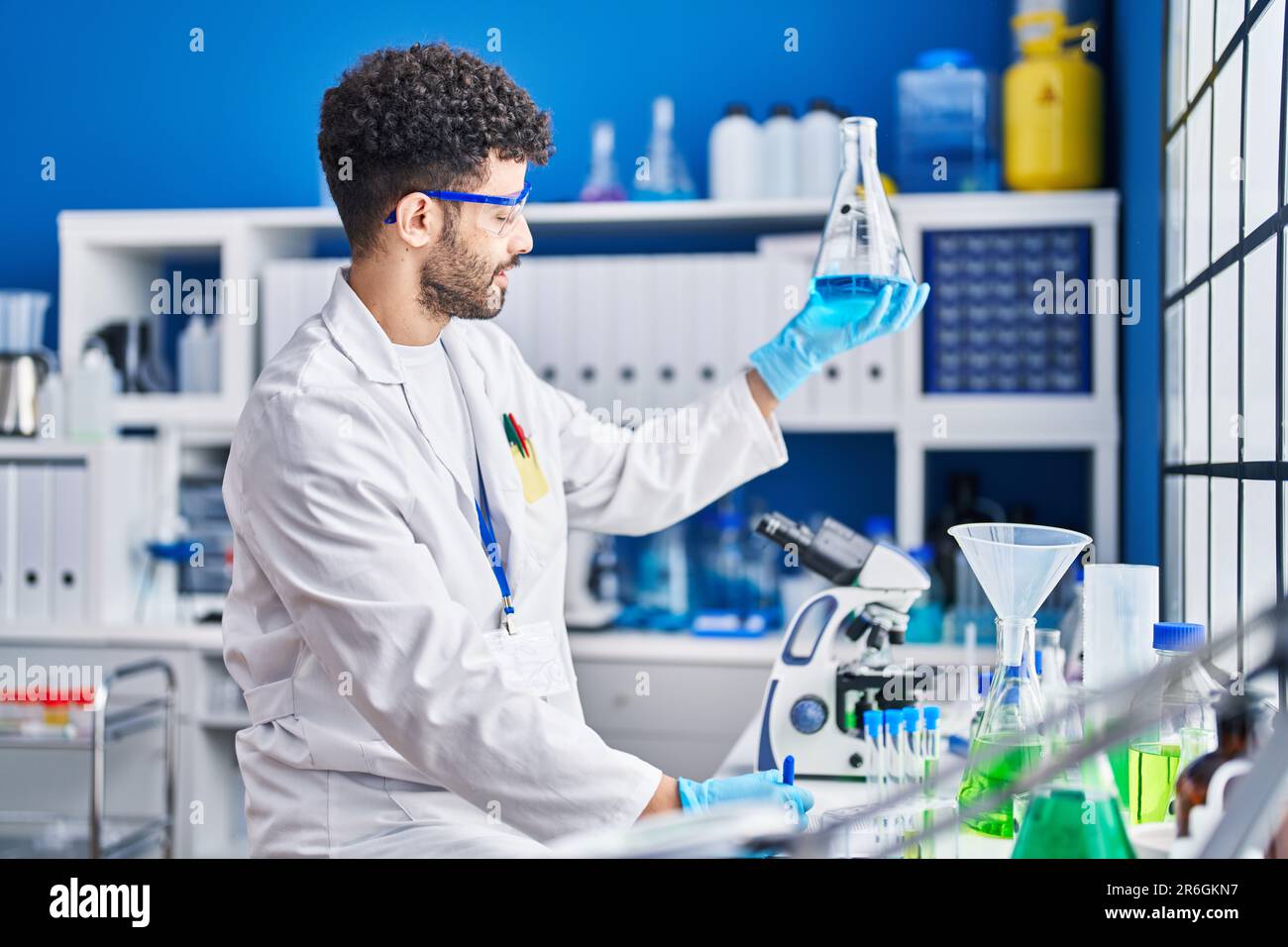 Young arab man wearing scientist uniform measuring liquid at laboratory Stock Photo - Alamy