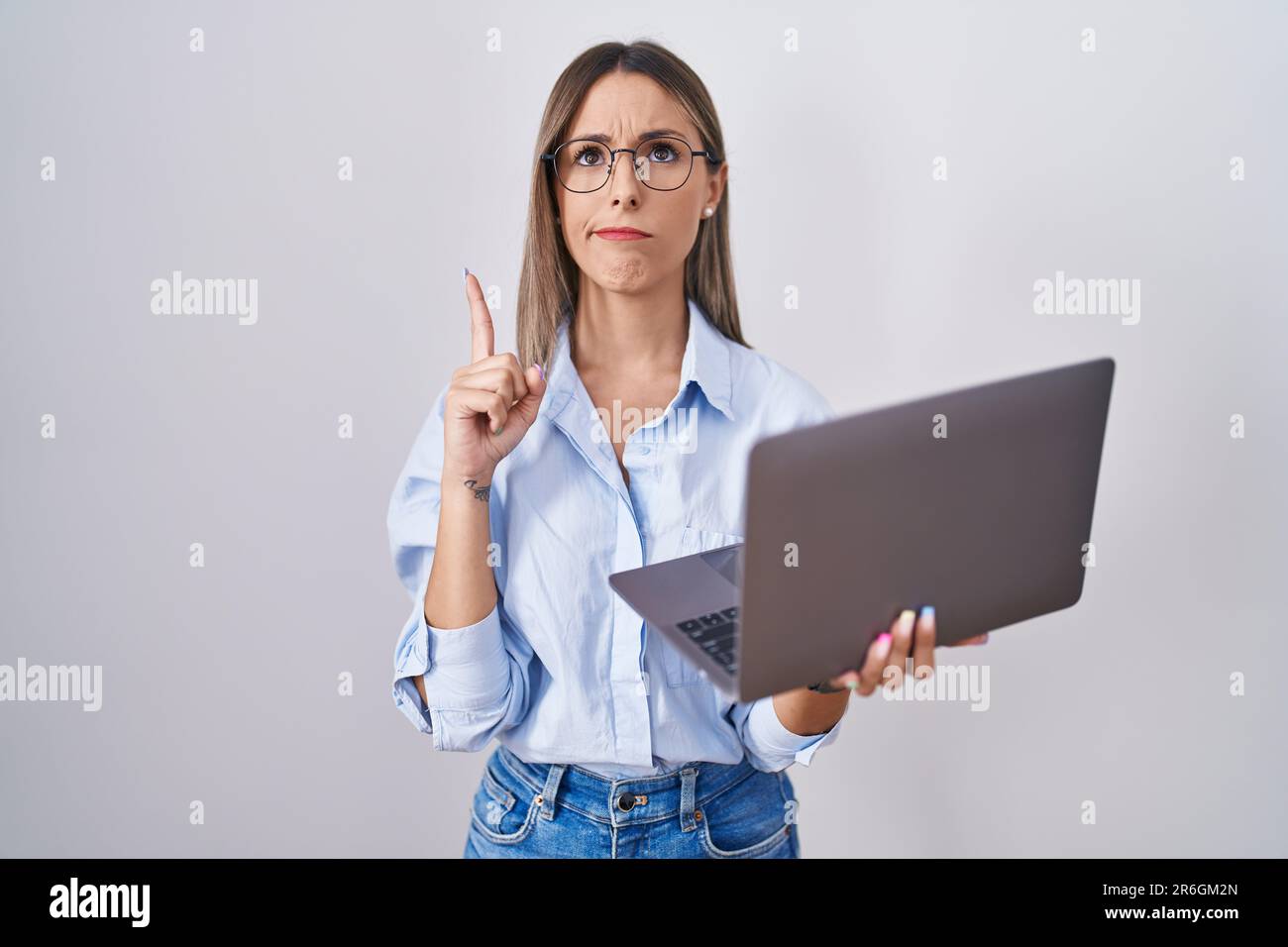 Young woman working using computer laptop pointing up looking sad and ...