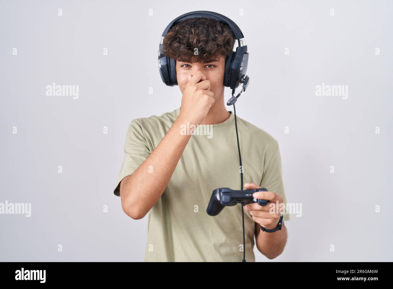 Hispanic teenager playing video game holding controller smelling ...